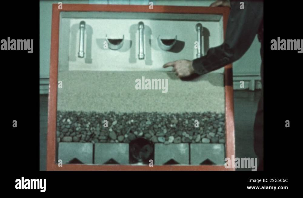 1950s: Man walks to board. Man moves hand down board showing water ...