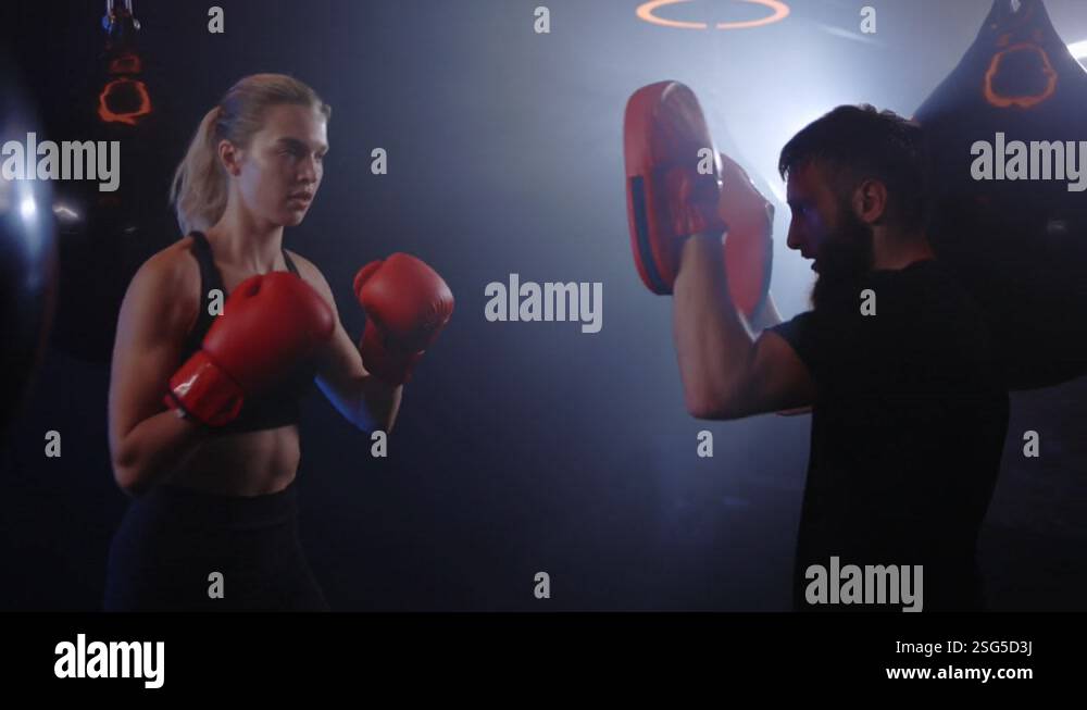 Caucasian female boxer is practicing work out boxing with personal ...