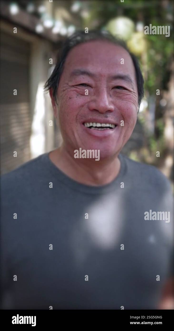 Portrait of a middle aged Asian American man smiling standing in street ...
