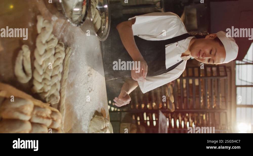 Vertical video of portrait of happy asian female baker preparing dough ...