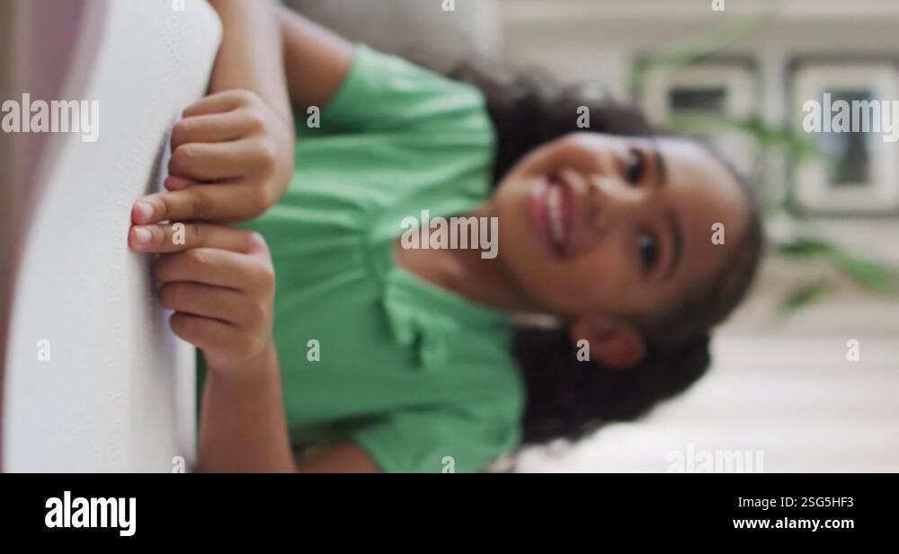 Vertical video of happy biracial girl with green dress reading braille ...