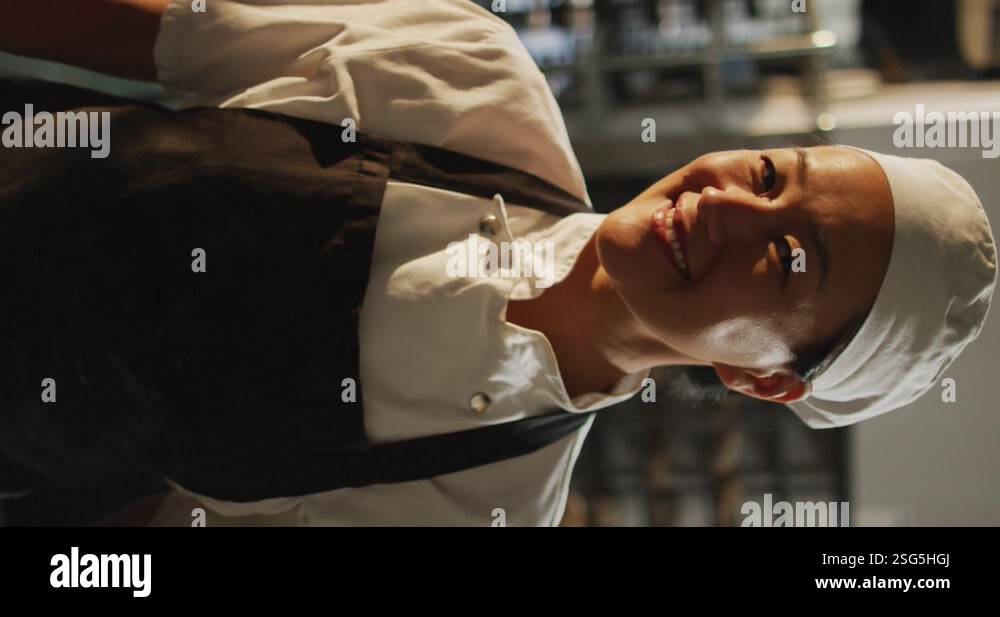 Vertical video of portrait of happy asian female baker in bakery Stock ...