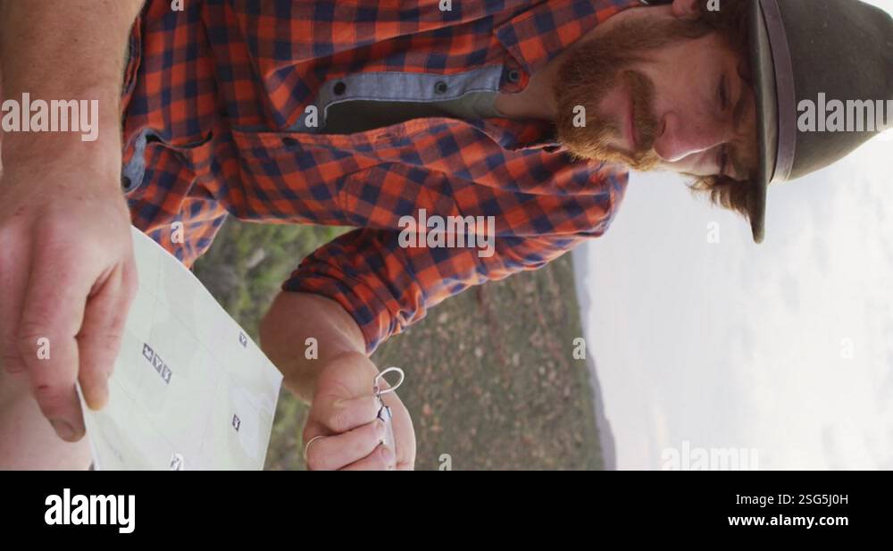 Vertical video of bearded caucasian male survivalist with map and ...