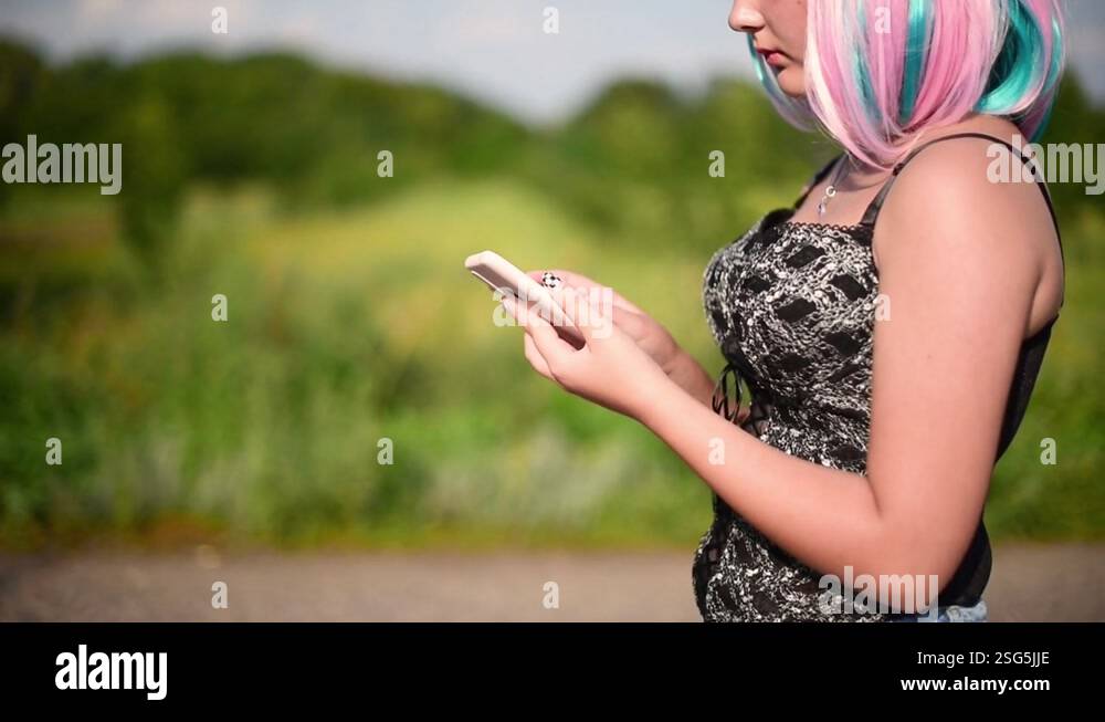 Cosplay, anime girl in pink wig typing telephone. Teenage girl uses ...
