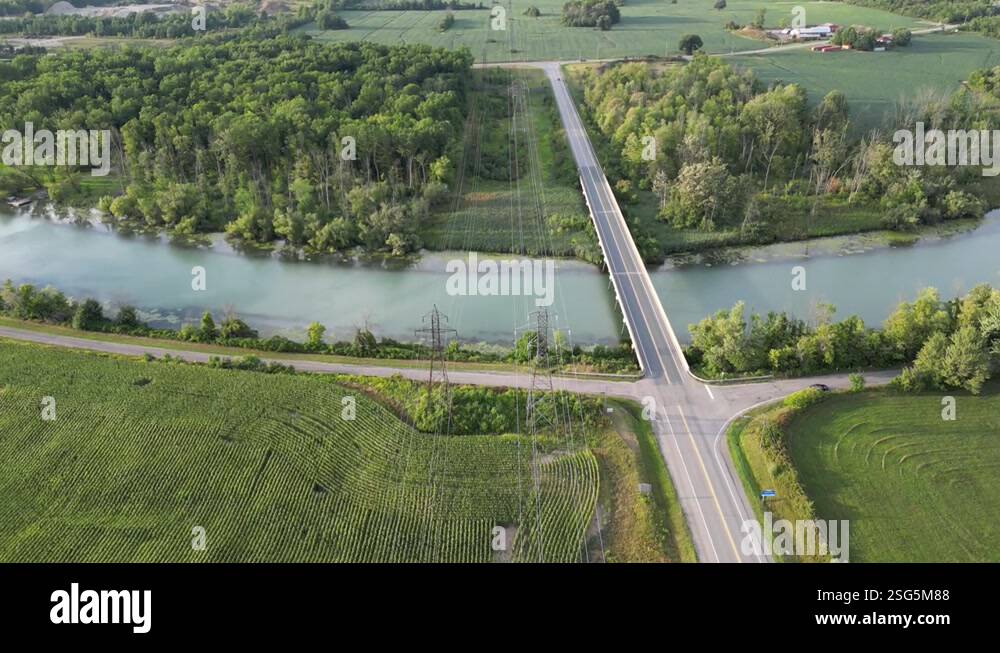 Power lines from grid over river water in rural countryside aerial tilt ...