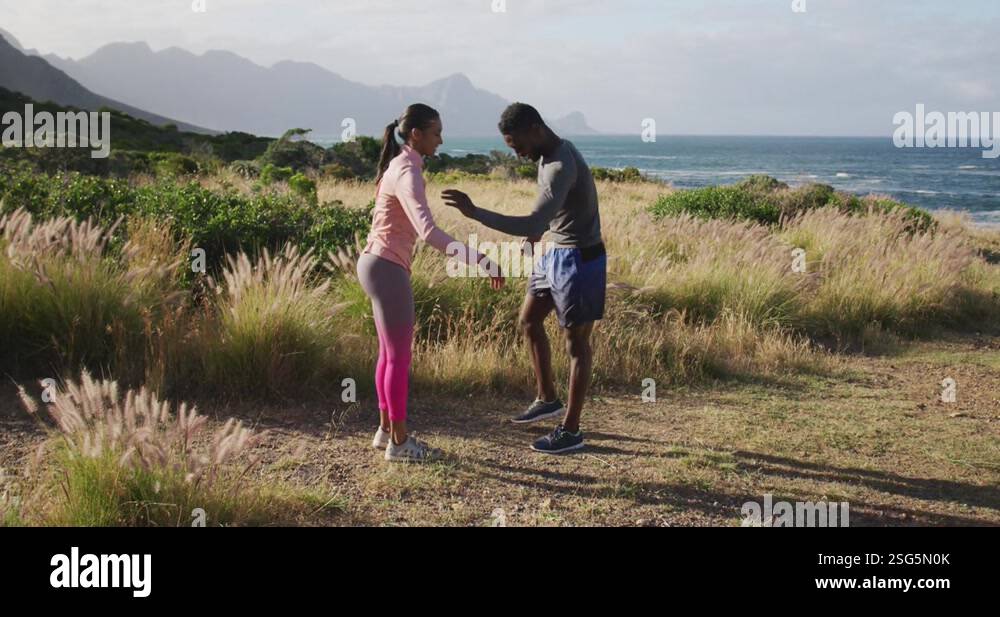 Diverse fit couple exercising stretching in a field in countryside ...