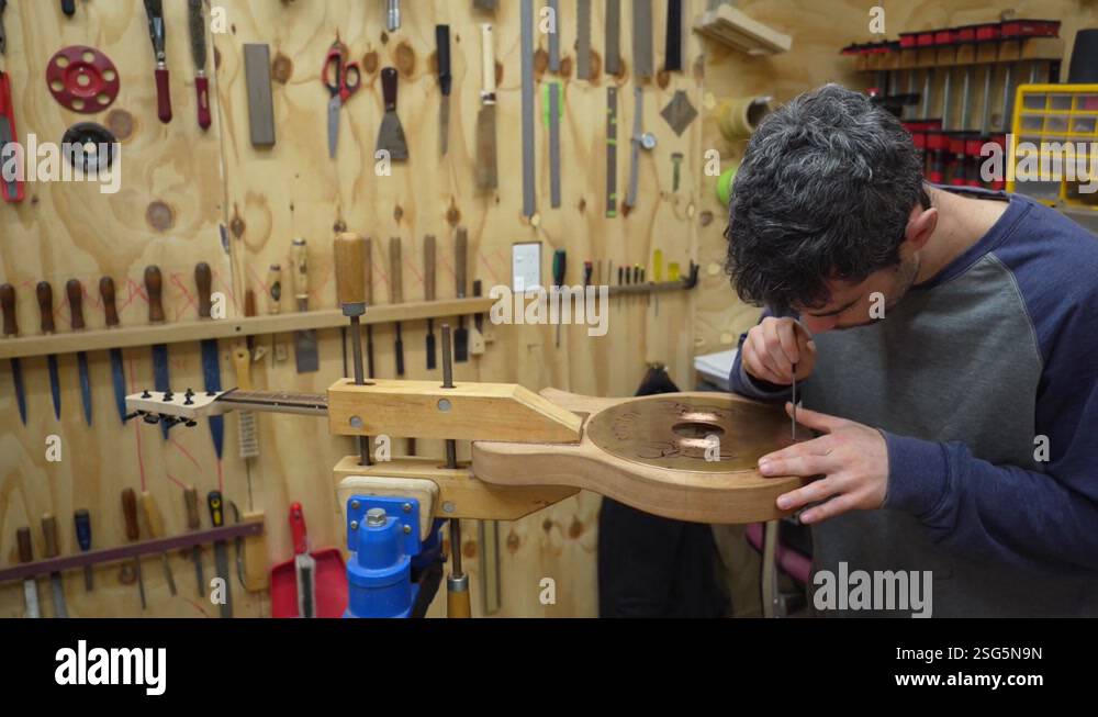 Luthier refining the slots by hand filing on cover plate attached to ...