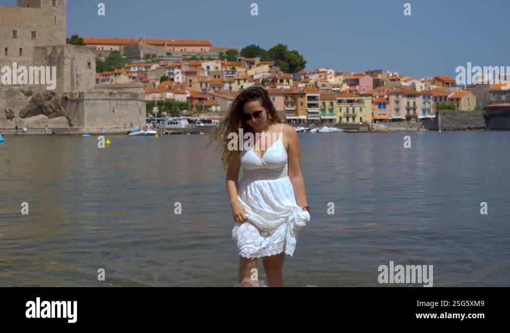 Cute girl walking slowly out of the bay of Collioure and playing with ...