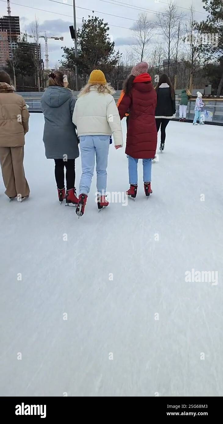 People skating on public open-air ice skating rink in city on winter ...