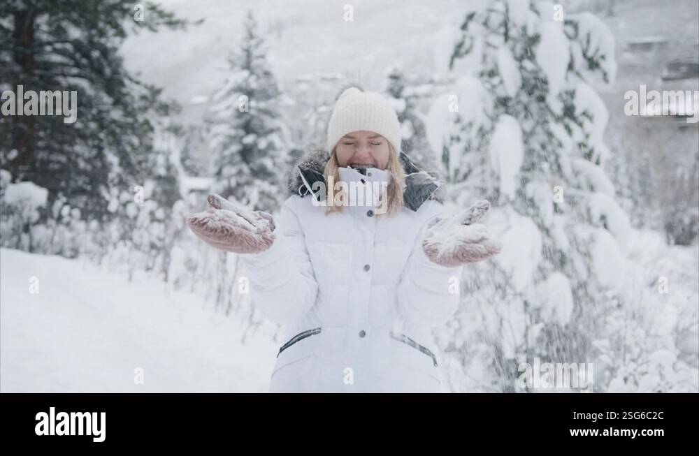 Slow motion young woman looks into camera and throwing bunch of snow ...