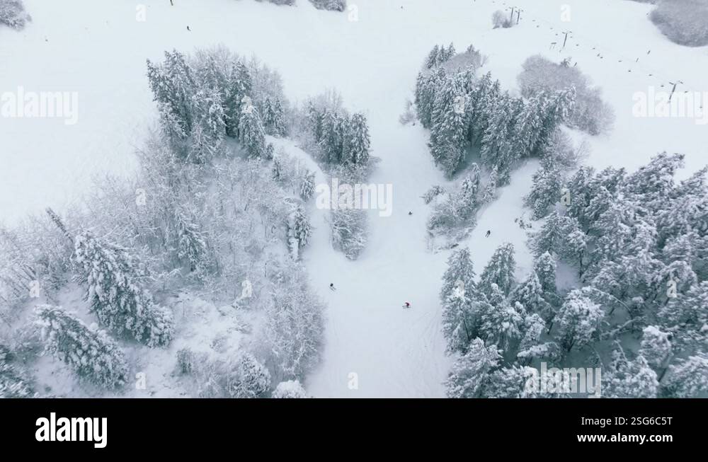 Aerial 4K winter ski resort footage with fast skiers riding down hill ...