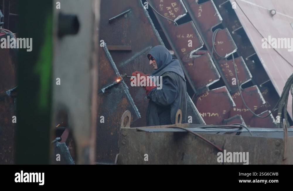 Welder working on welding cargo ship together. loads of sparks flying ...