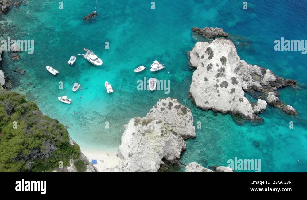 Multiple boats are sailing in the crystal blue as seen from the cliff ...