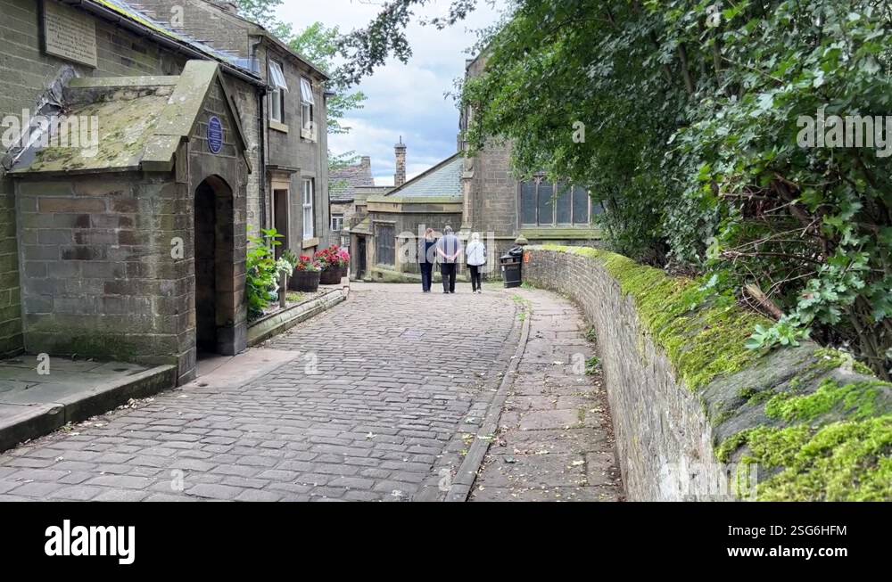 Walking along a Haworth street with cobbled road and and people walking ...