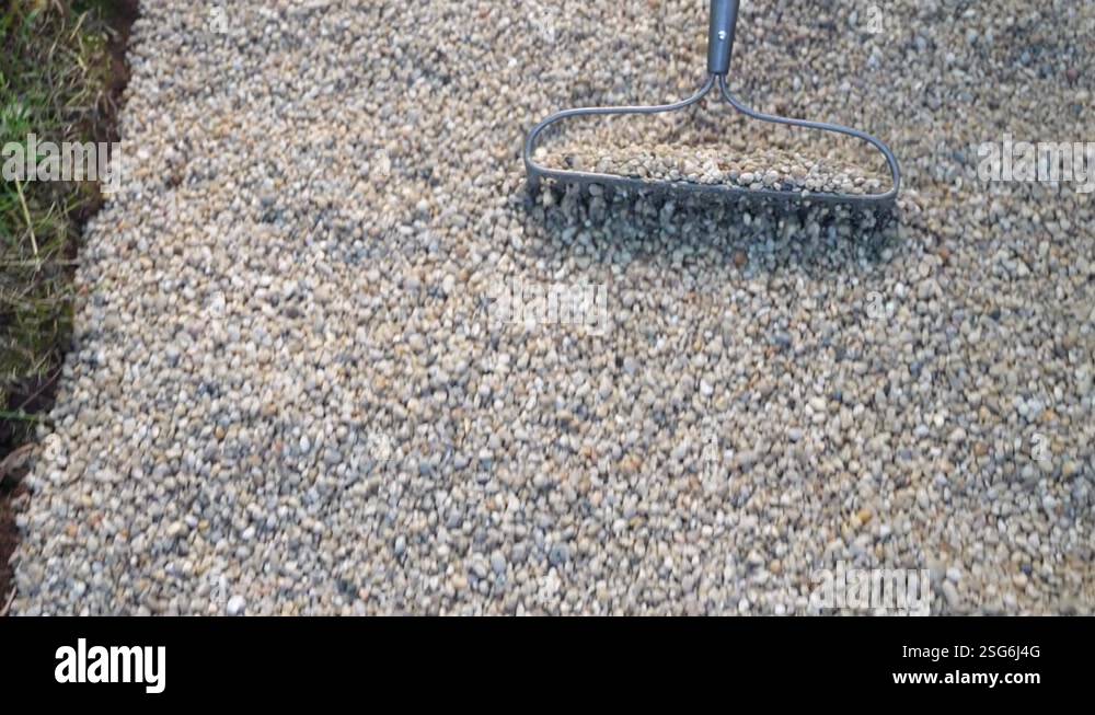 Slow motion raking pea gravel stone on top of landscape fabric for a ...