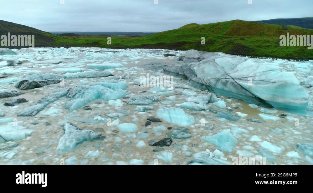 Ice fragments floating over a freezing lake near green ridges Stock ...
