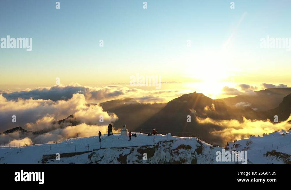 Drone shot flying backwards over a group of people on top of a mountain ...