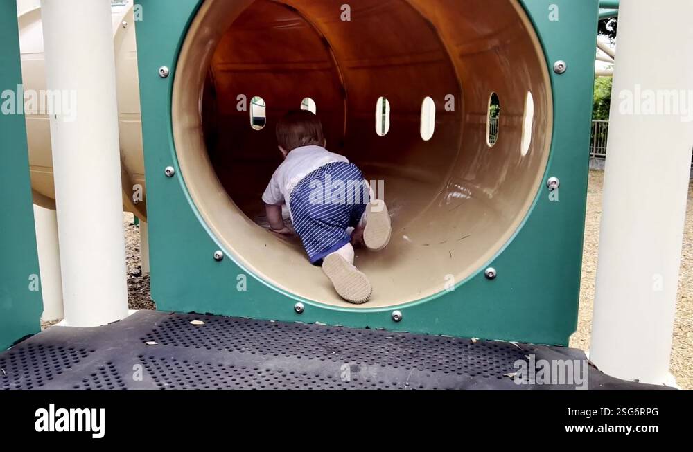 Toddler crawling through tunnel on playground Stock Video Footage - Alamy