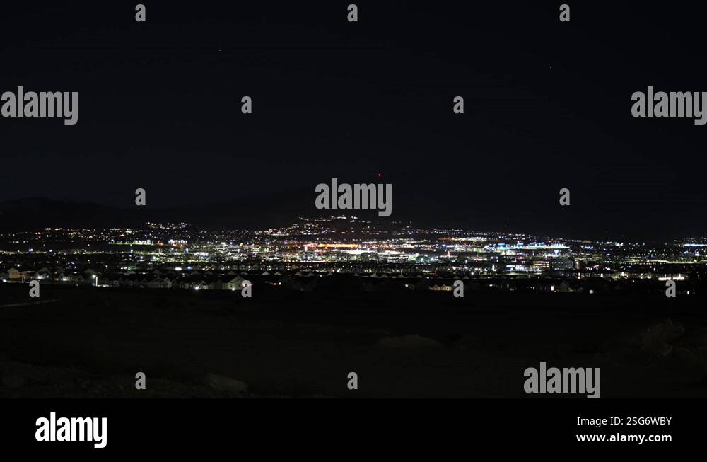 City lights from a distant town in a valley beneath the mountains at ...