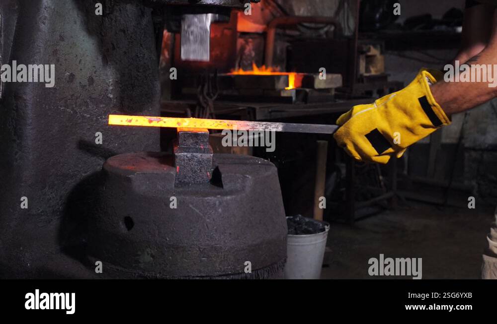 A blacksmith processes a red-hot billet in a mechanical hammer in the forge Stock Video Footage ...