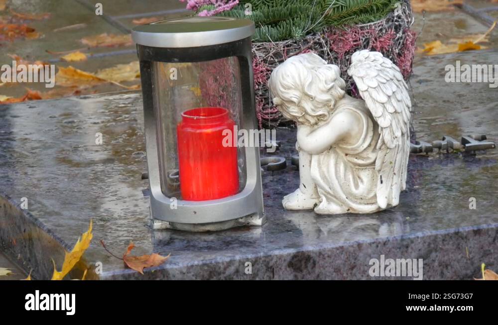 Red memorial candle burning with fire on rainy day on tombstone in ...