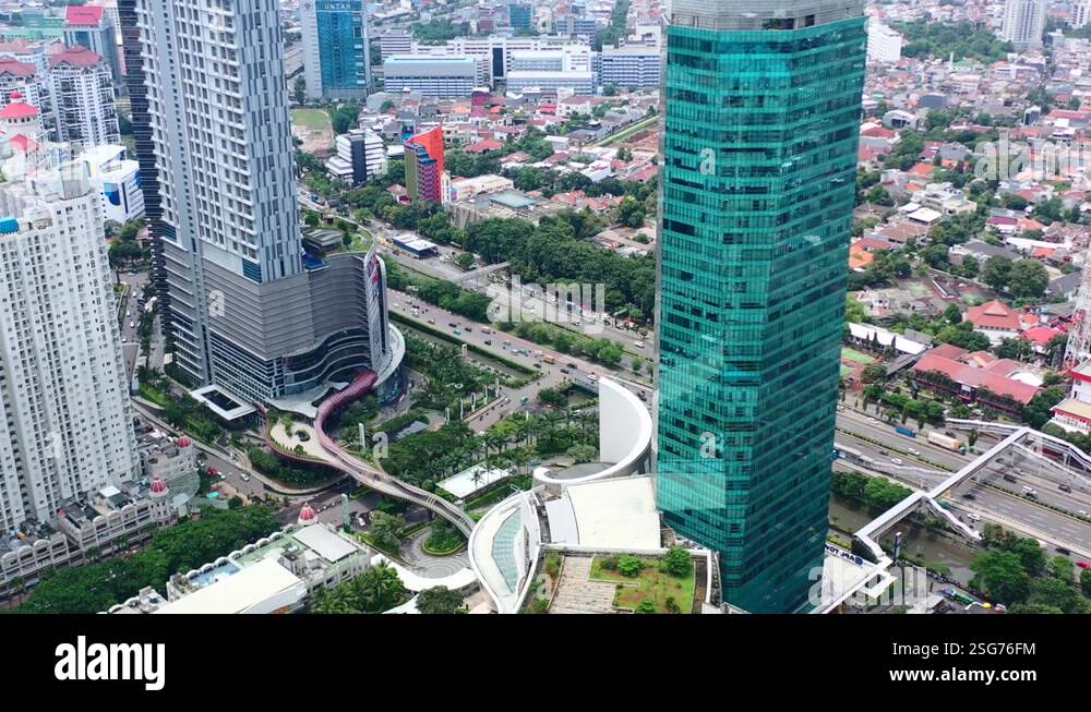 tall high-rise commercial buildings and mall near highway with vehicles ...