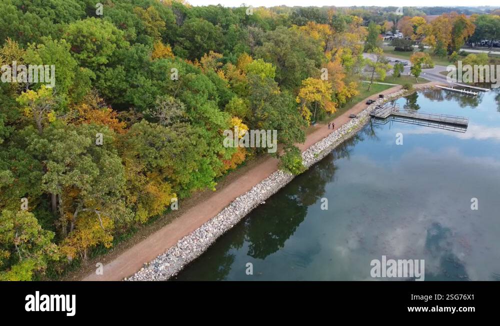 People walking on a trail around a lake during the fall next to a ...
