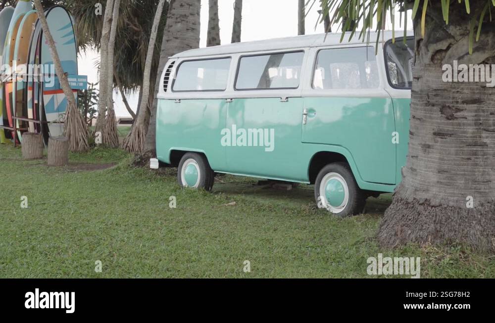 A pan reveal shot of a classic VW Bus on a beach with surfboards, a ...