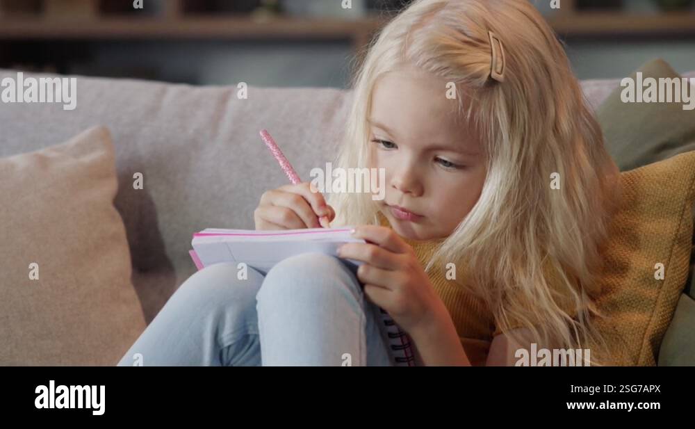 Preschool girl writing in notepad and training handwriting, sitting on ...