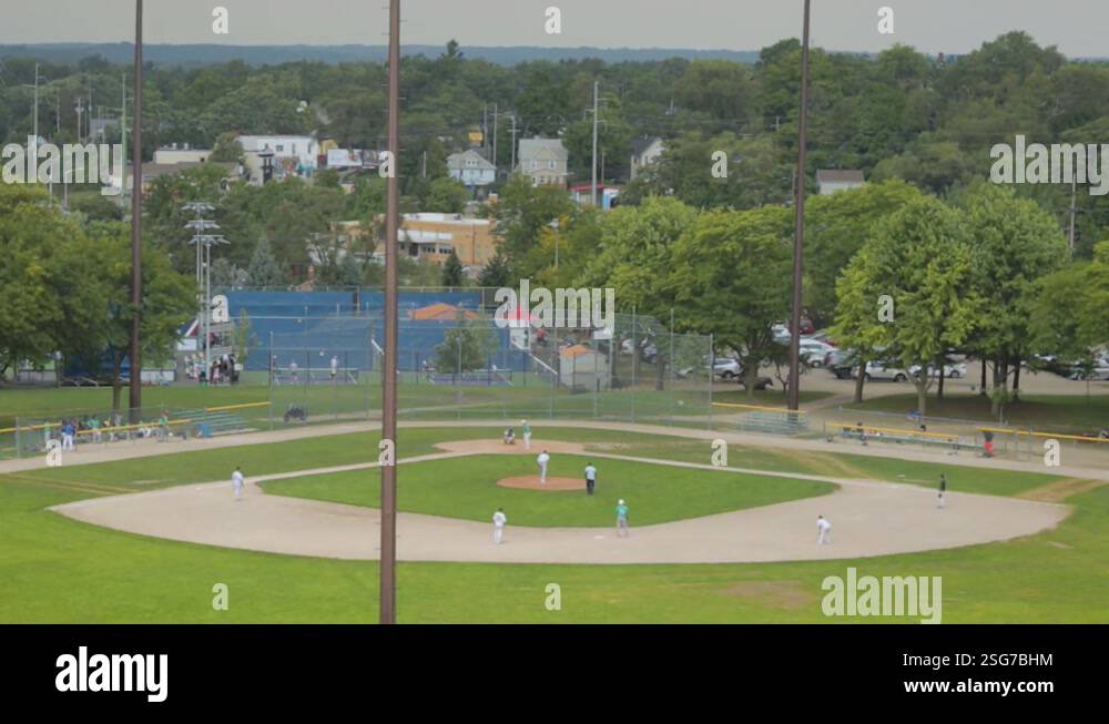 Two Teams Compete On Baseball Field During Hot Afternoon In Small Town ...