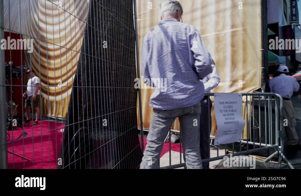 A Security Guard lets a man through a gate to the Oscar's red carpet ...
