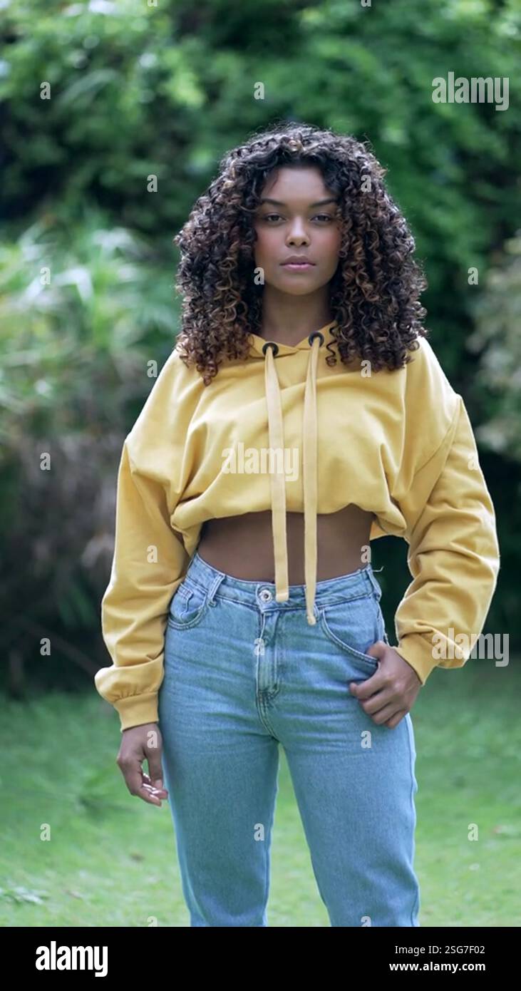 A young black hispanic latina 20s girl standing outdoors looking at ...