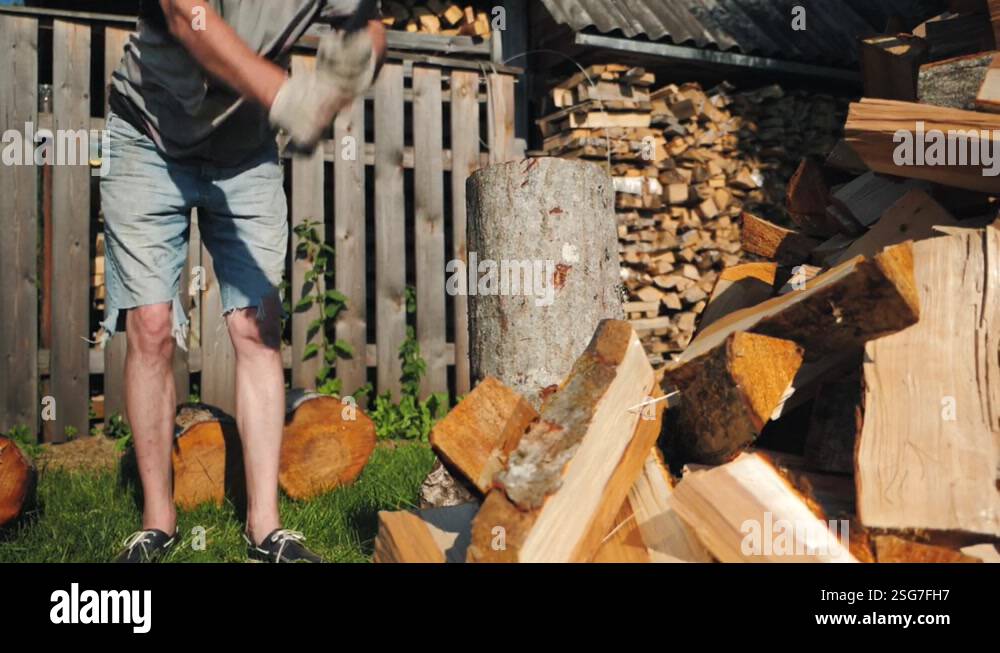 Strong male worker chopping wood, swinging and hitting wooden log with ...