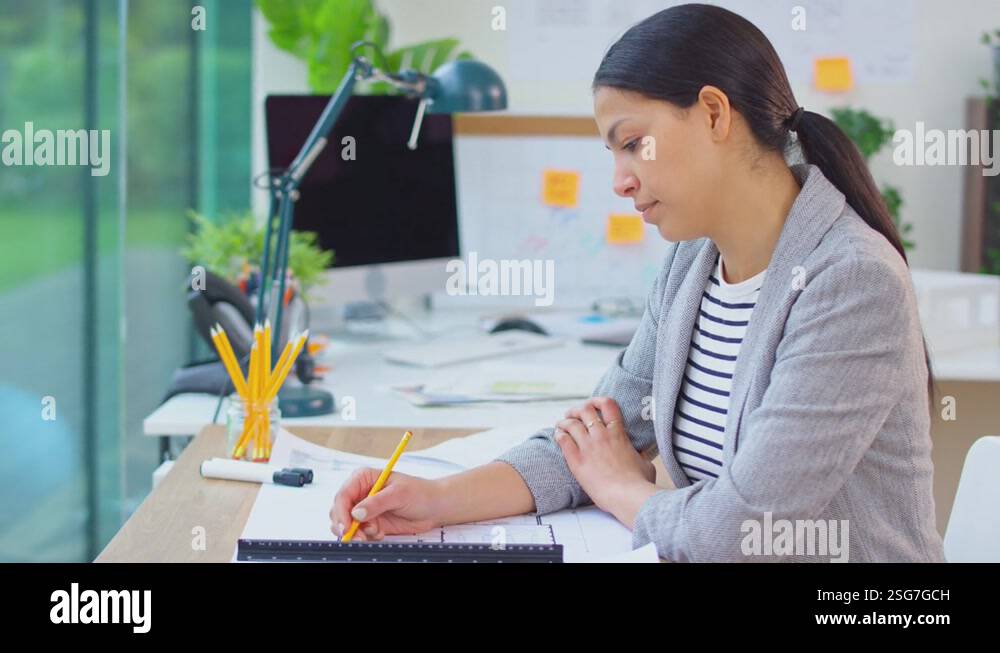 Female Architect In Office At Desk Working On Plans For New Building ...