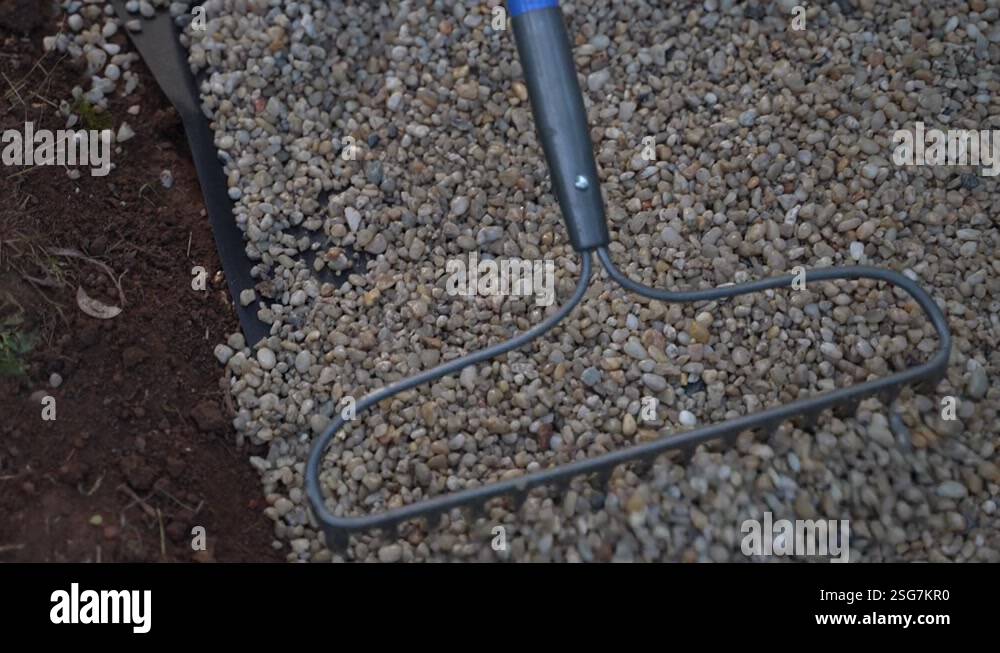 Slow motion raking pea gravel stone on top of landscape fabric for a ...