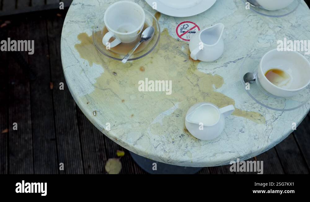 Spilled coffee on a marble table at an outdoor cafe with a No Smoking ...