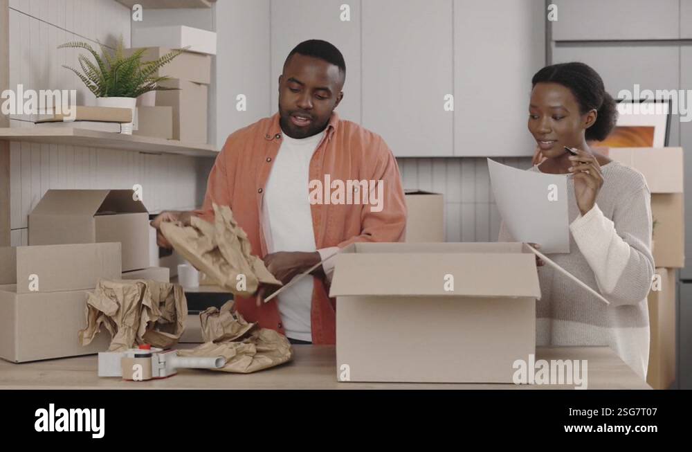 African american couple packing the dishes to the boxes and the woman ...