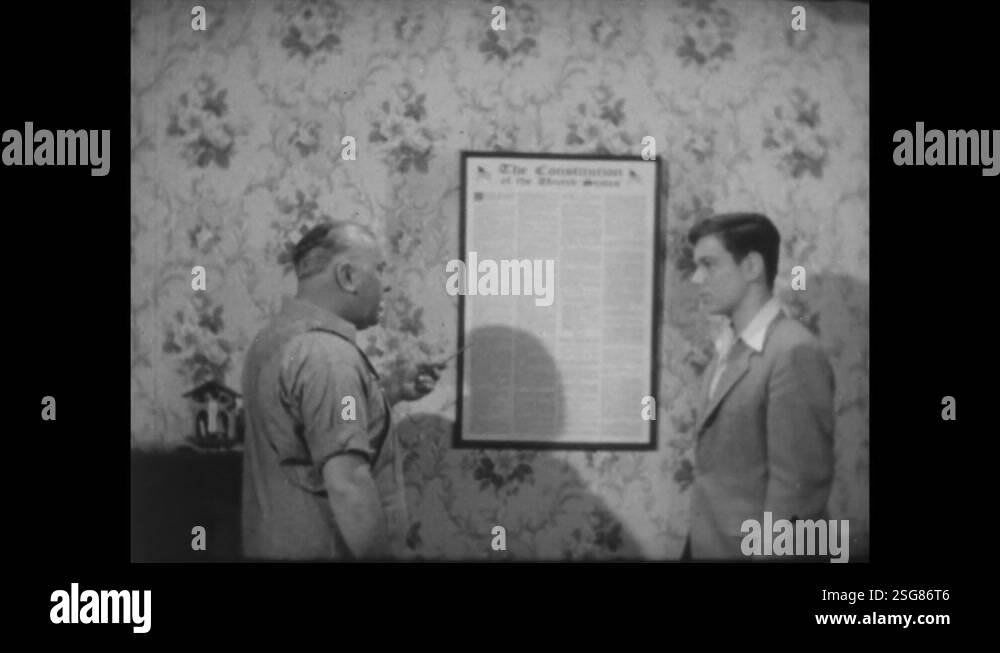 1940s: Man and boy point to framed constitution and talk. Screwdriver ...