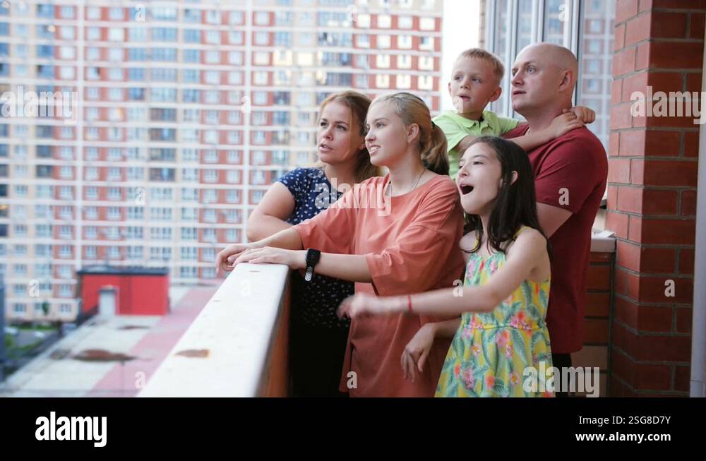 A happy family of 5 people look at the neighborhood from the balcony of ...