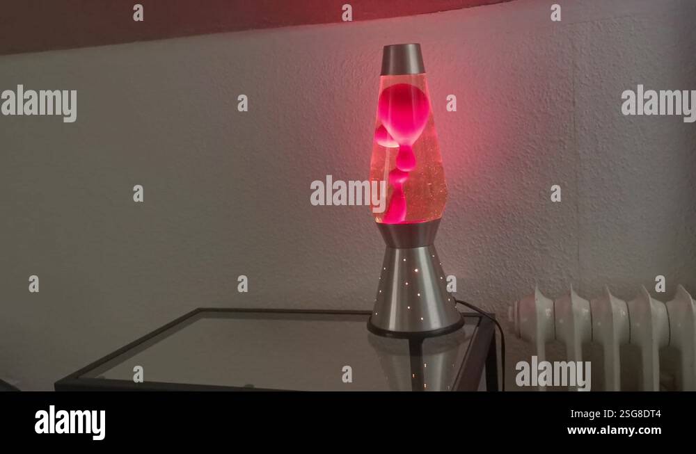 Glowing, bubbling lava lamp standing on a glass table next to a wall ...