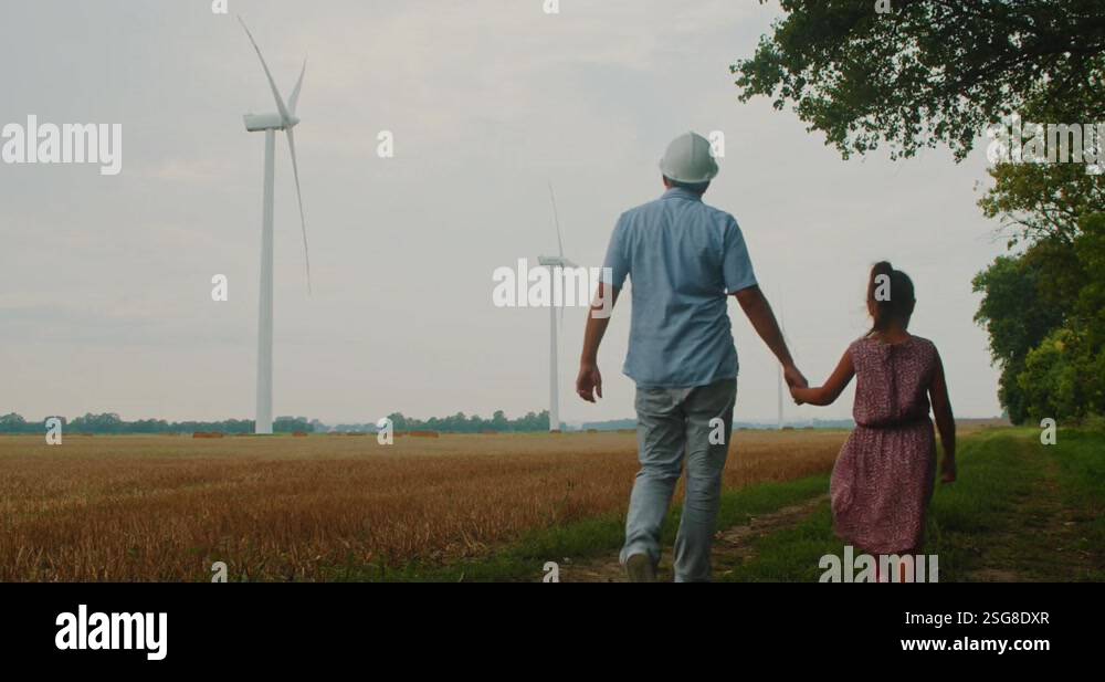 Engineer's father and his little daughter are walking in a field with ...