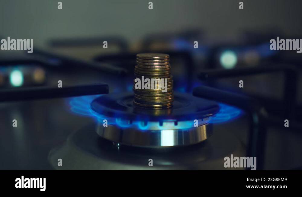 Gas cooker with burning flames of blue propane gas with stack of coins ...