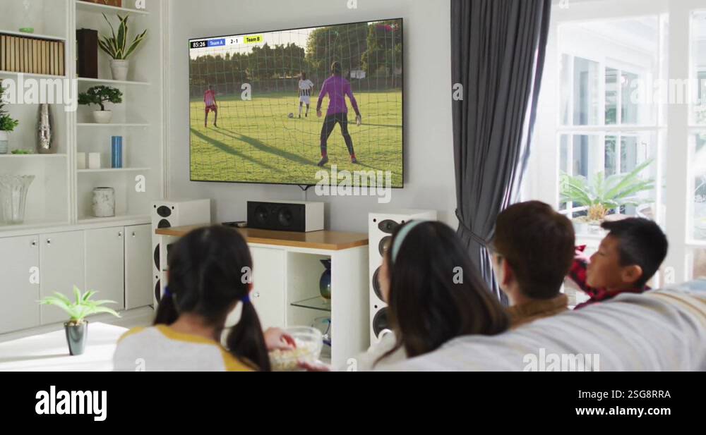 Asian family watching tv with diverse male soccer players playing match on Stock Video Footage ...