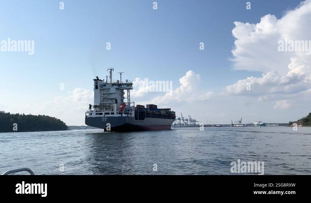 Cargo ship with containers filmed arriving to harbour from a sea level ...