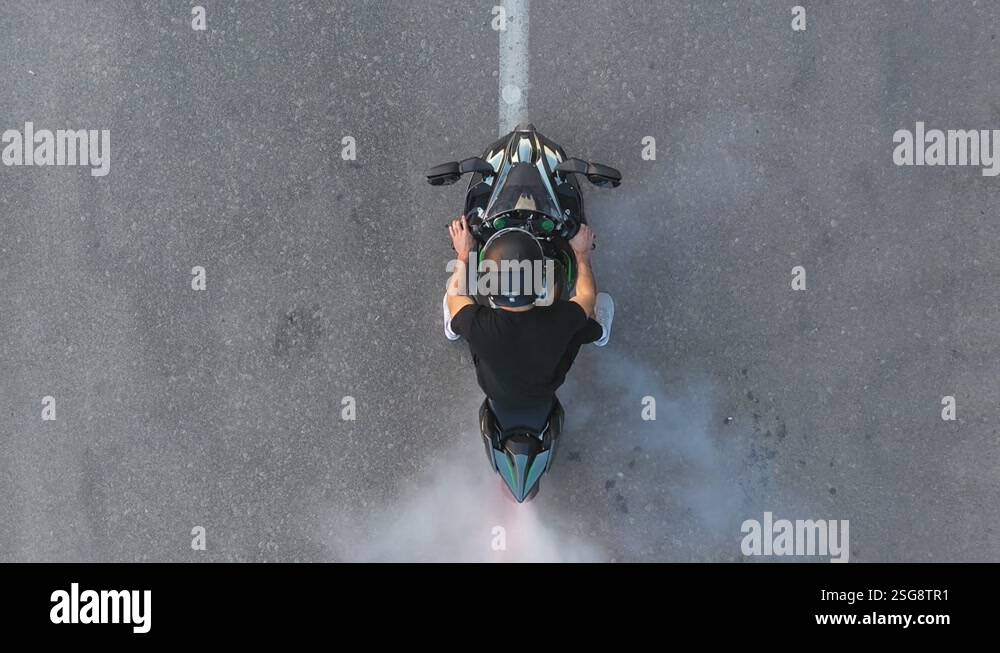 Top view of biker performing tire burnout with lots of smoke. Wheel are ...