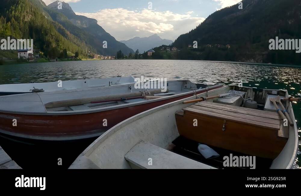 Boats floating on the shore of Lake Alleghe in the Italian Alps on a ...