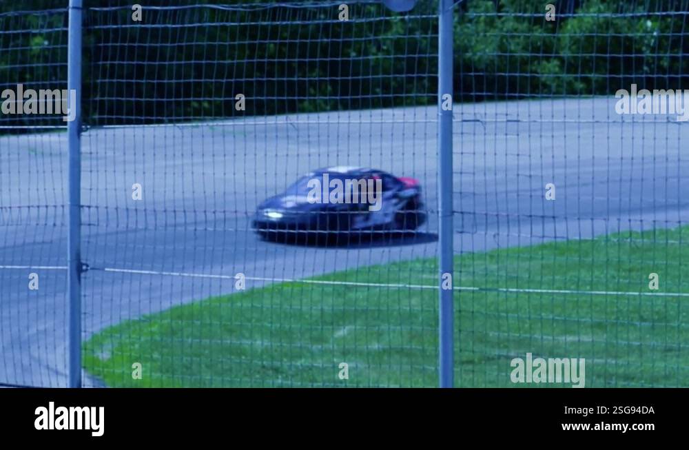 Race car driving around track. Green Car coming into frame left to ...
