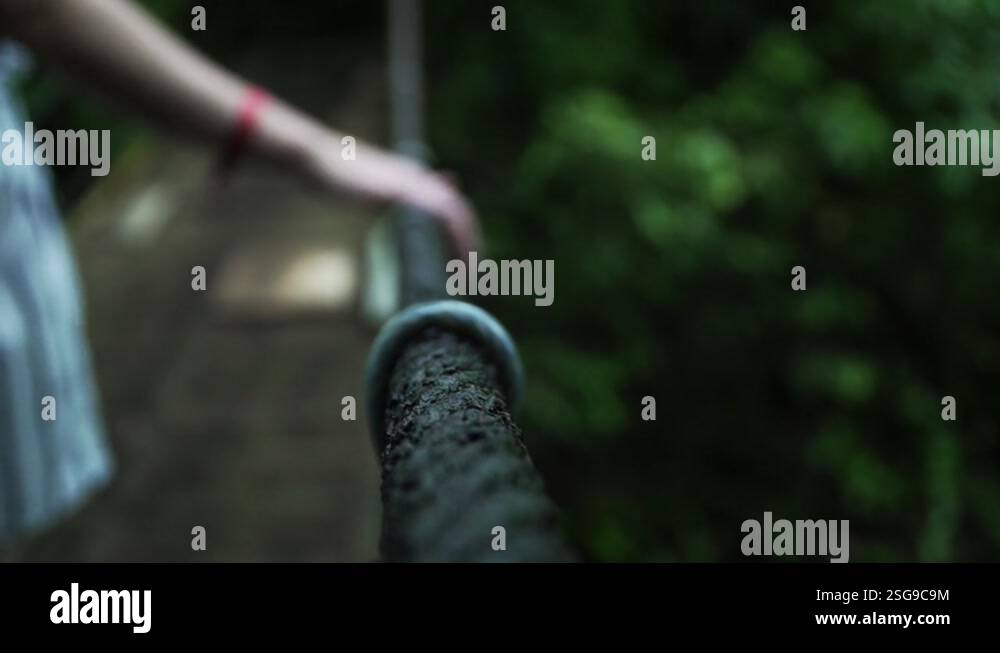 Lady's hand holding on to a rope of a hanging rope bridge as she ...