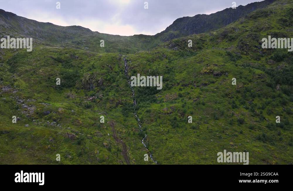 Ascending aerial view of a cascade flowing over the saddle edge of a ...