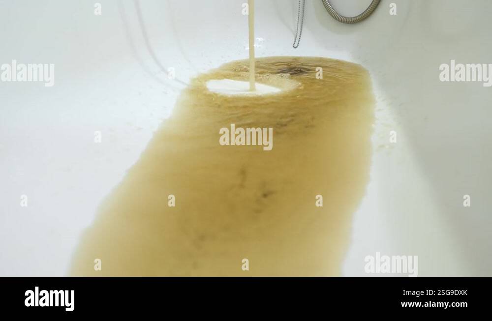 Rusty water running from the tap in a bath. Hazardous tap water flows ...